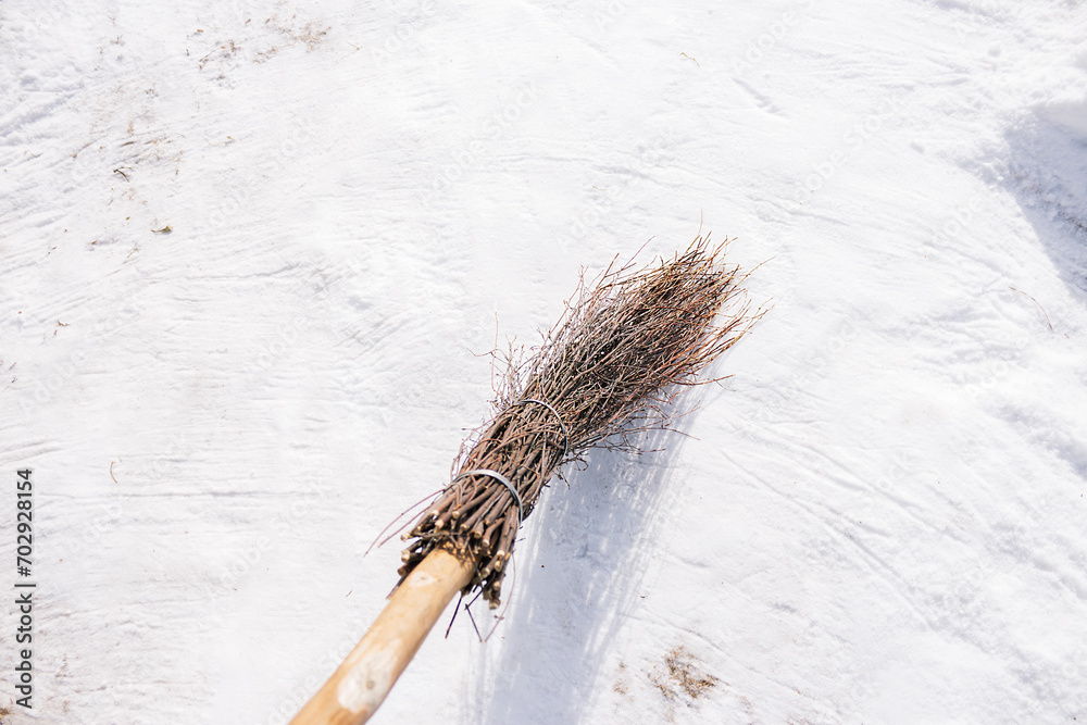 clearing snow from paths with a broom from branches. The way to the ...