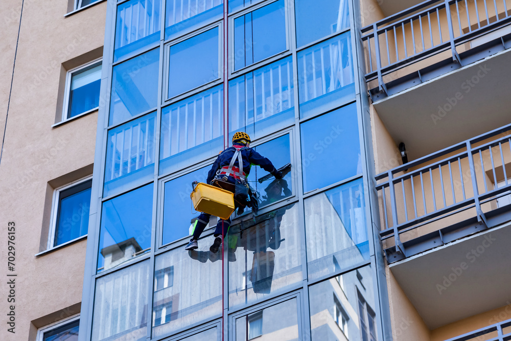 Foto de Bottom view of male rope access laborer in work uniform washing ...