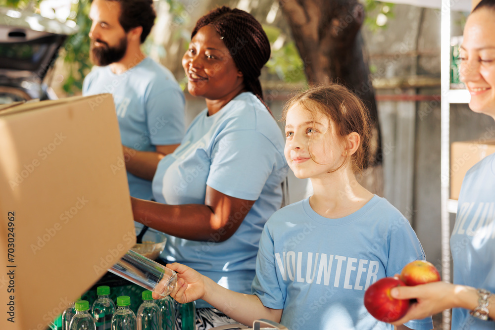 Photo focus on young volunteer girl sharing water and neccesities to ...