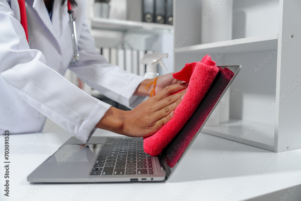 medical professional, likely a female doctor, sanitizing a desk with a ...