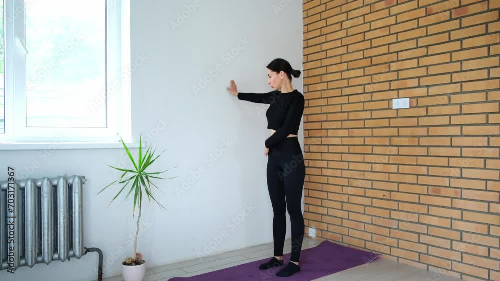 Slim sporty 30s woman lean her hand on the wall and rising leg. Workout ...