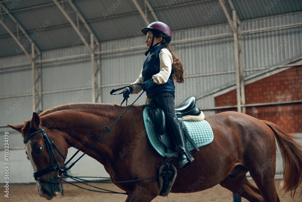 Little girl, kid, equestrian sitting in special uniform and helmet on ...