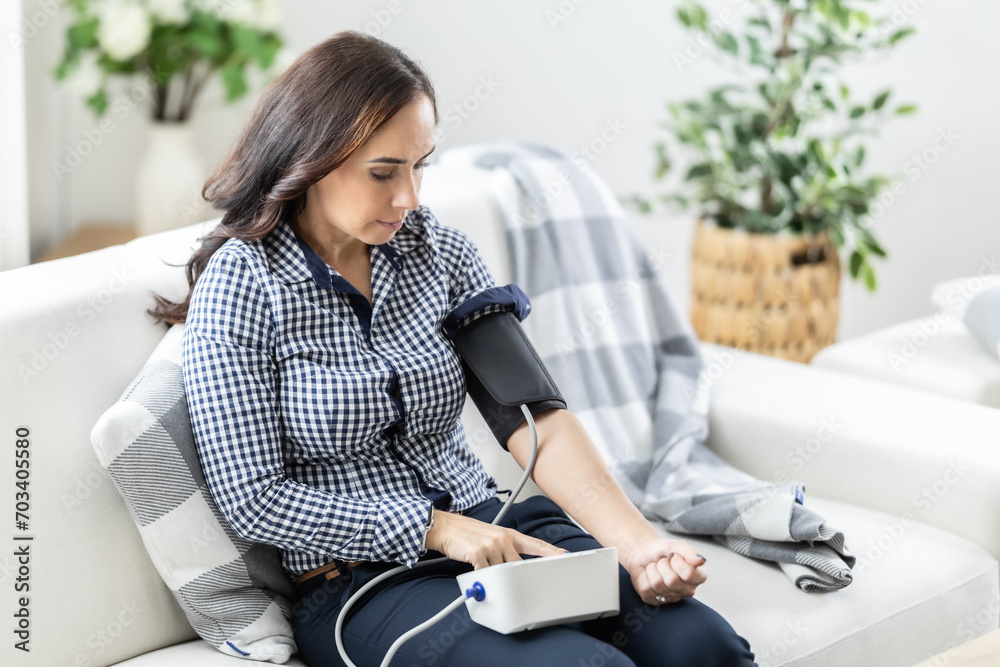 Beautiful woman checking her blood pressure at home with a digital ...