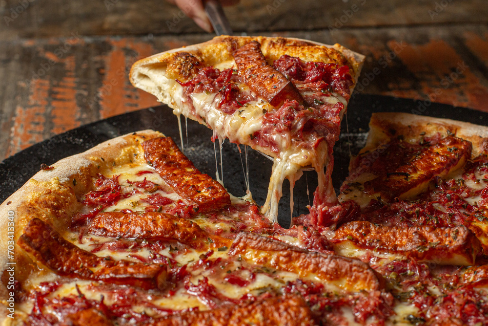 .slice of dried meat and cheese pizza served very hot with melting ...