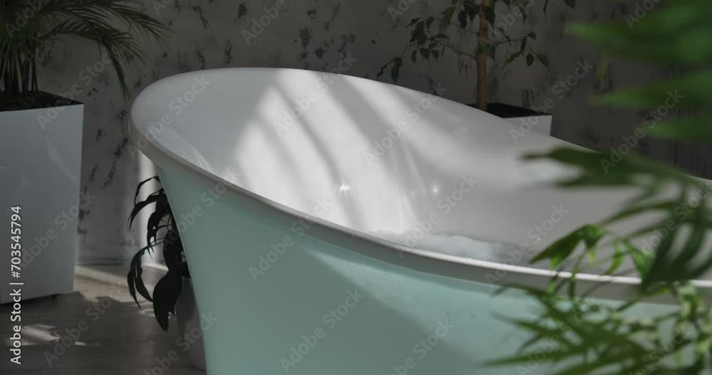 Glamorous shiny white bathtub filled with clear water for relax and spa ...