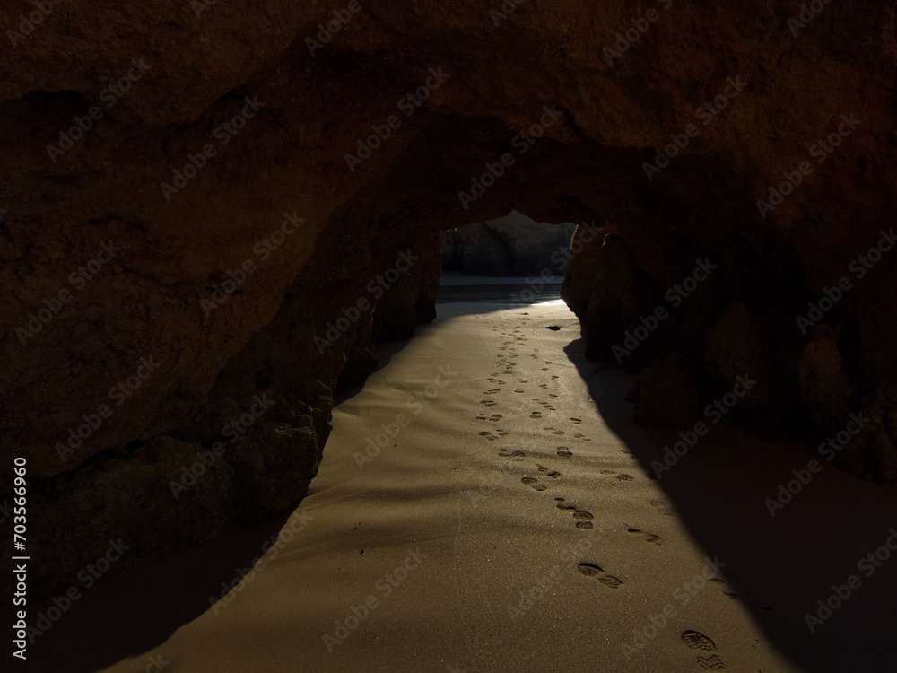 Ray of light entering a cave on the beach, creating a path of light on ...