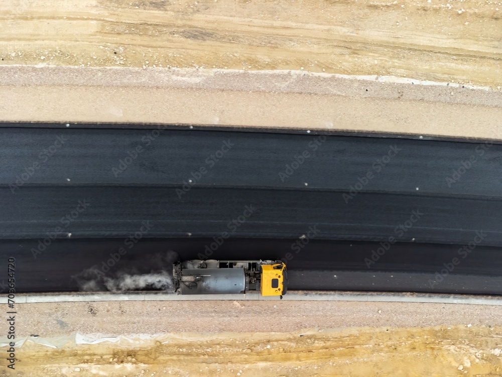 yellow truck pouring bitumen over a new road. Aerial drone shot. Road ...