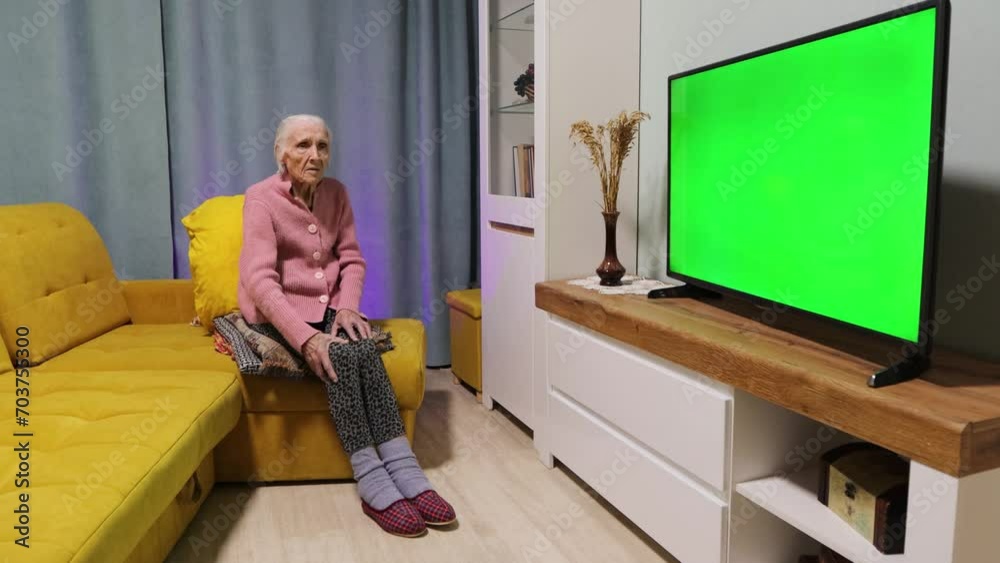 Grandma is watching TV. Green screen. Grandma is sitting on the sofa at ...