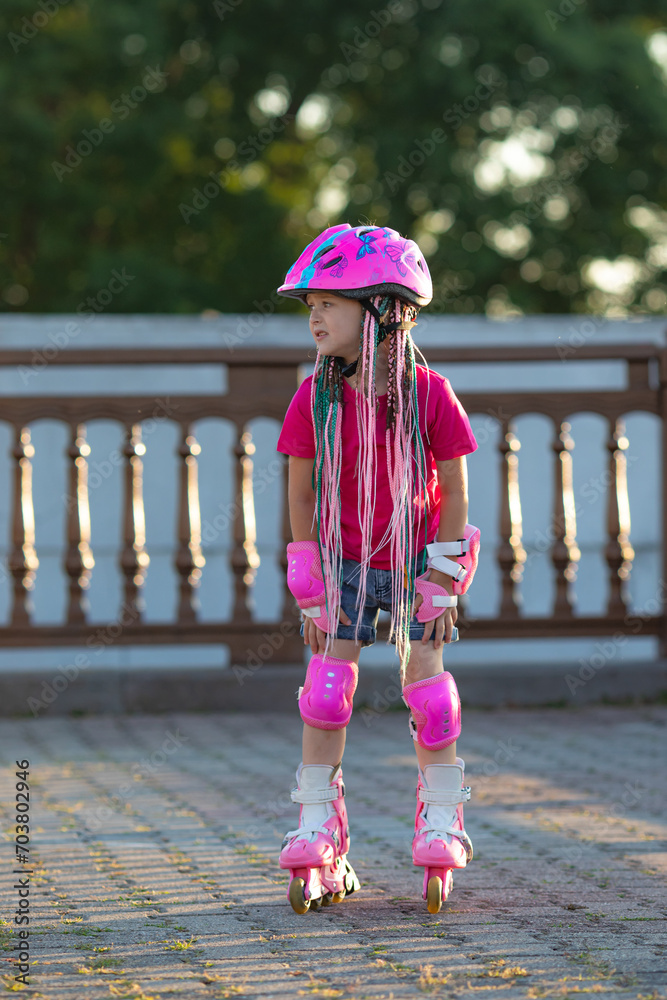 Foto de Sad little pretty girl on roller skates in helmet at a park ...