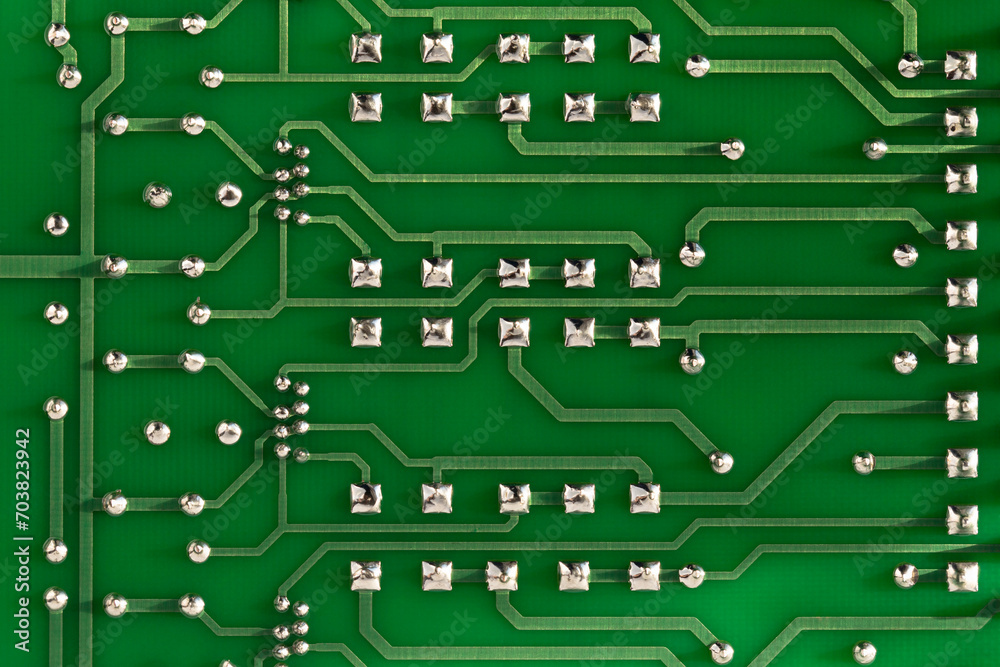Conductor traces with silver drops of solder on a green electronic ...