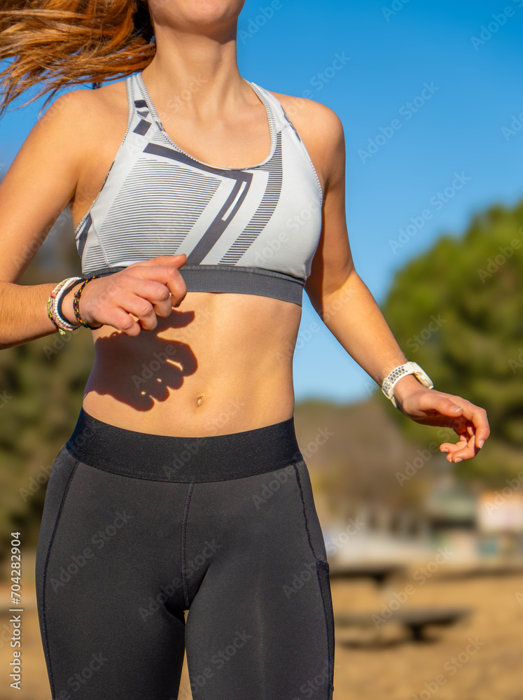 Part of torso of a young muscular female runner, running dressed in ...