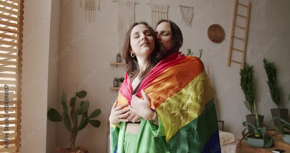 Female lesbian couple standing wrapped in rainbow lgbt flag, embracing ...