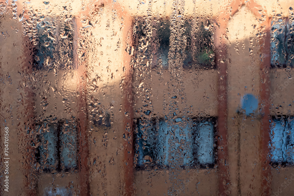 Condensation droplets on the interior of a single pane window with red ...
