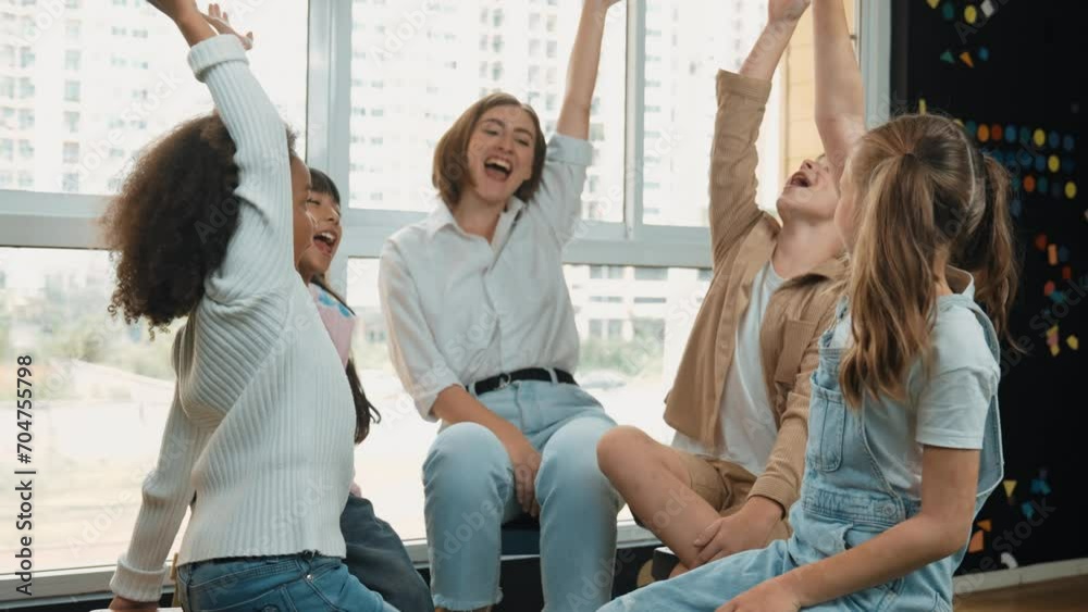 Teacher and diverse students putting hands together at classroom. Young ...