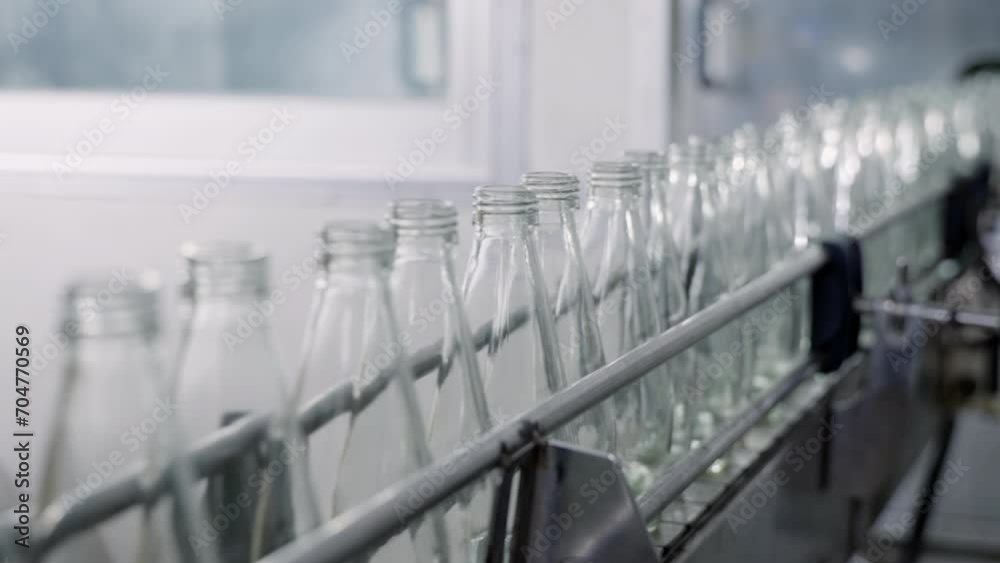 In a distillery an automated belt exhibits empty glass bottles hinting ...