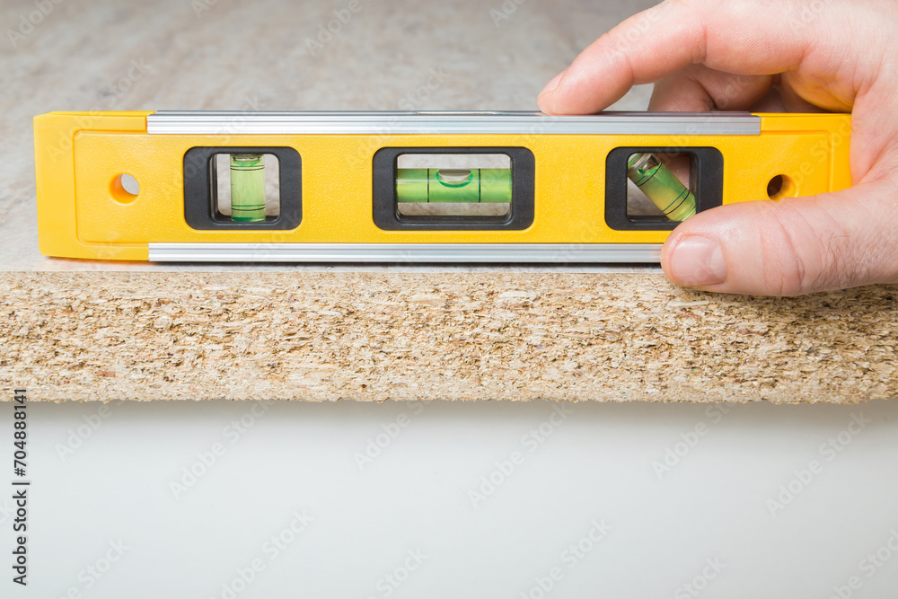 Young adult man hand using yellow spirit level and measuring horizontal ...