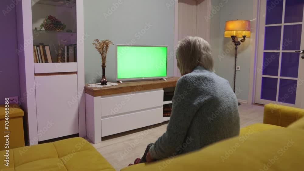 Grandma is watching TV. Green screen. Grandma is sitting on the sofa at ...