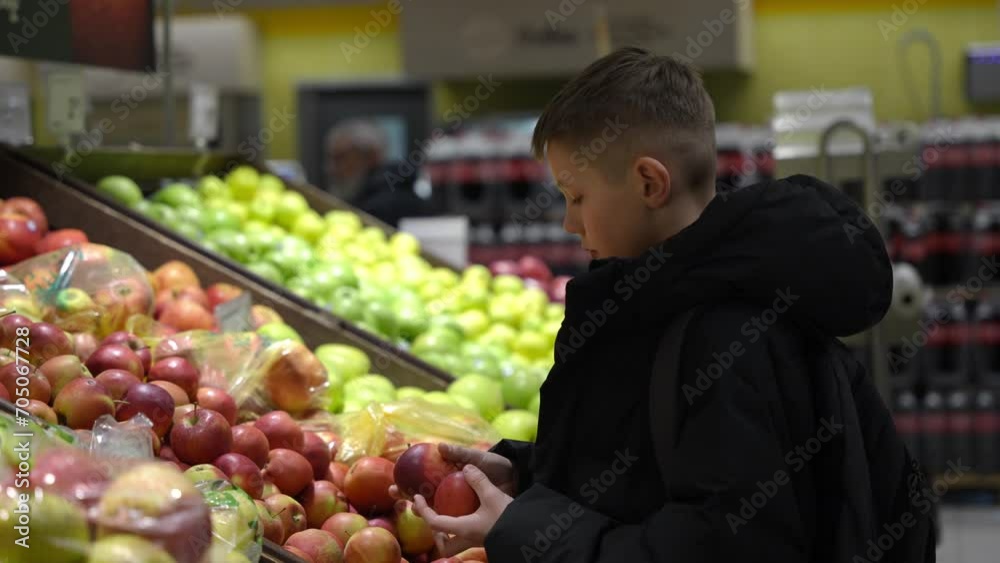 Vidéo Stock Young boy trying to decide which apple to pick. Teen boy at ...