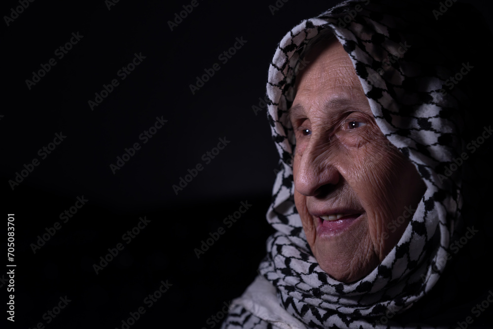 portrait of an old lady in dark background wearing white palestinian ...