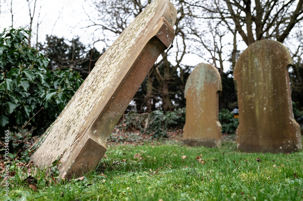 Shallow focus of a stone grave seen heavily leaning over due to ground ...