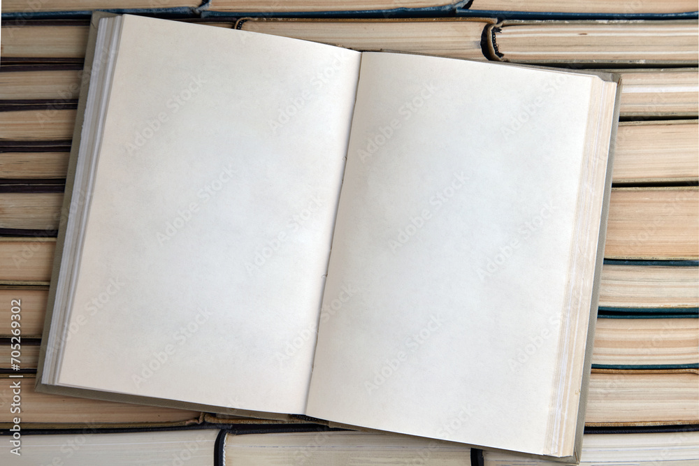 Opened diary with blank pages to place text on a stack of paper books ...