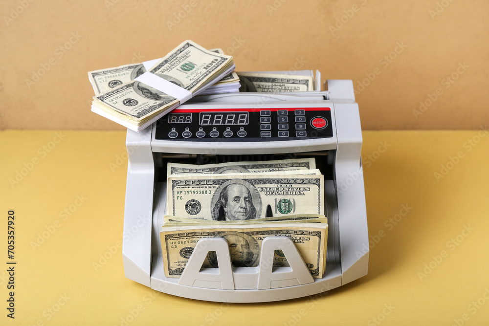Modern cash counting machine with dollar banknotes on color background ...