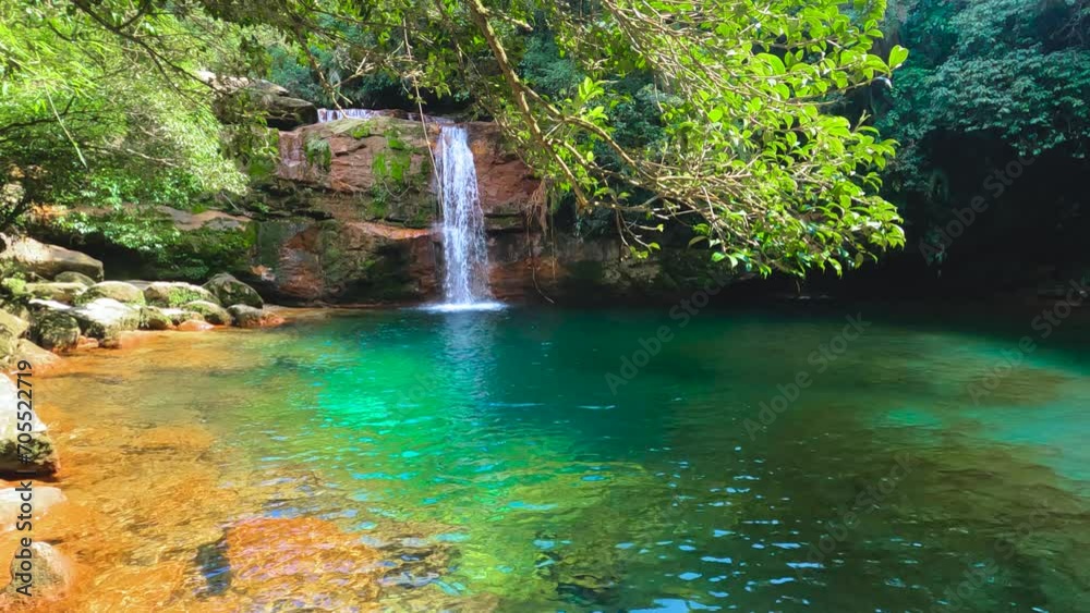 Jungle waterfall with white waters running down Rocky ridge of hill to ...