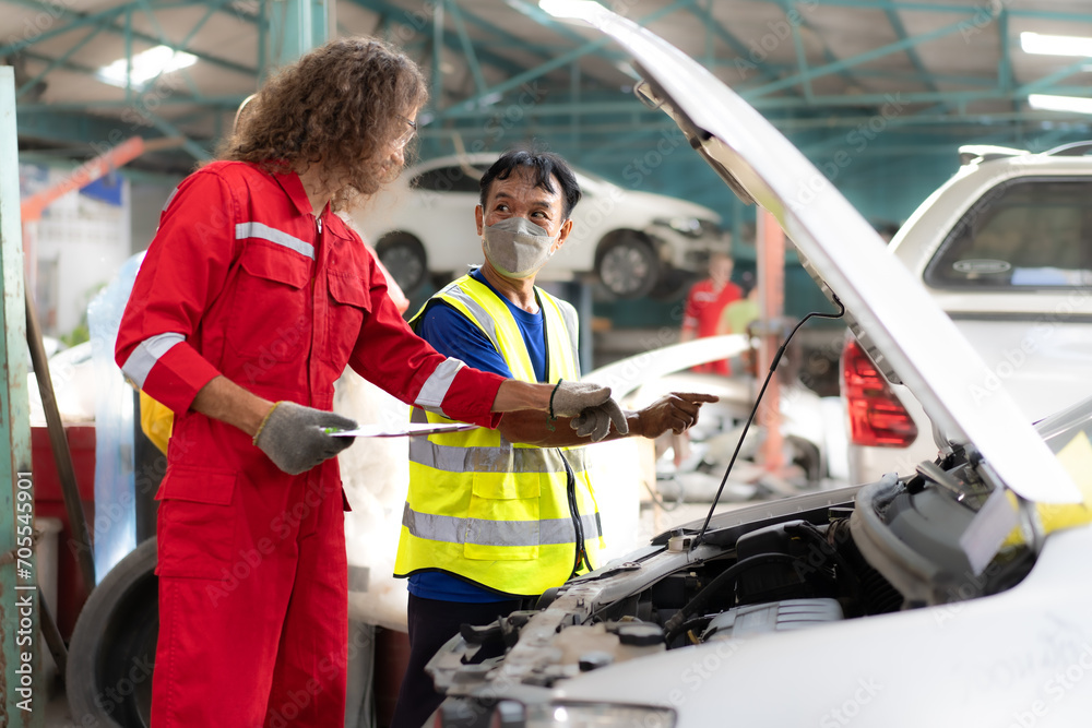 Caucasian auto mechanic checking broken car engine and talking ...