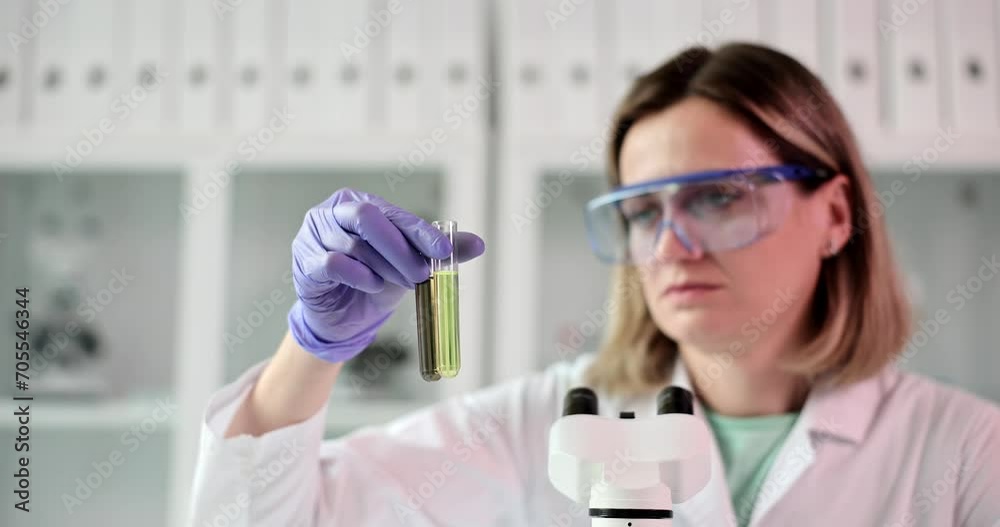 Chemist compares colors of two chemical liquids in test tubes ...