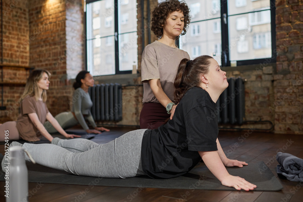 Side view of young female fitness instructor helping girl with ...