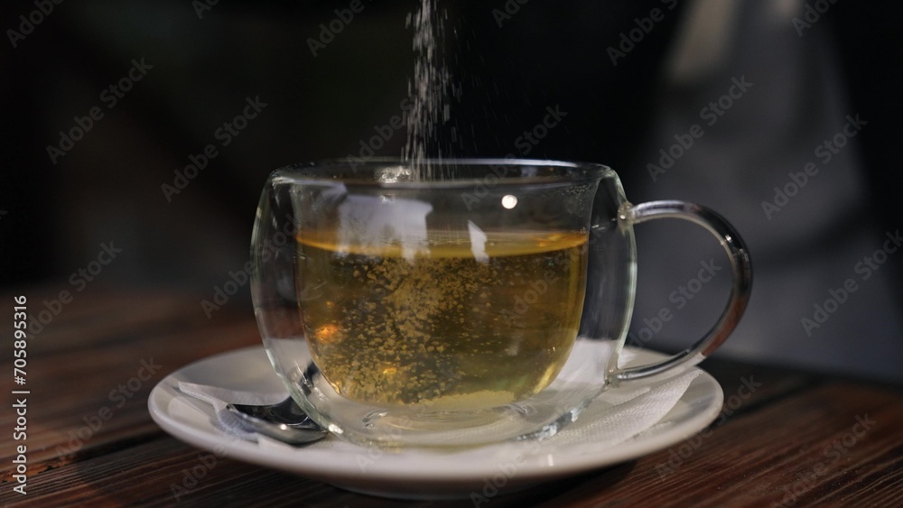 Person adding sugar into green tea in transparent cup at wooden table ...