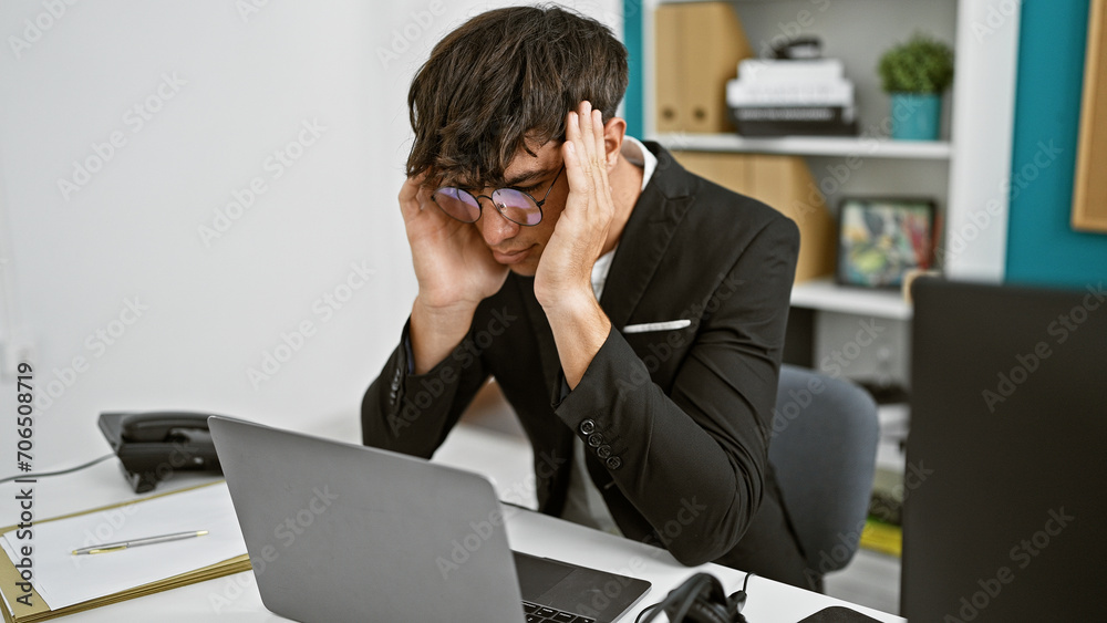 Young, stressed hispanic teenager battling work stress as he juggles being a business worker ...