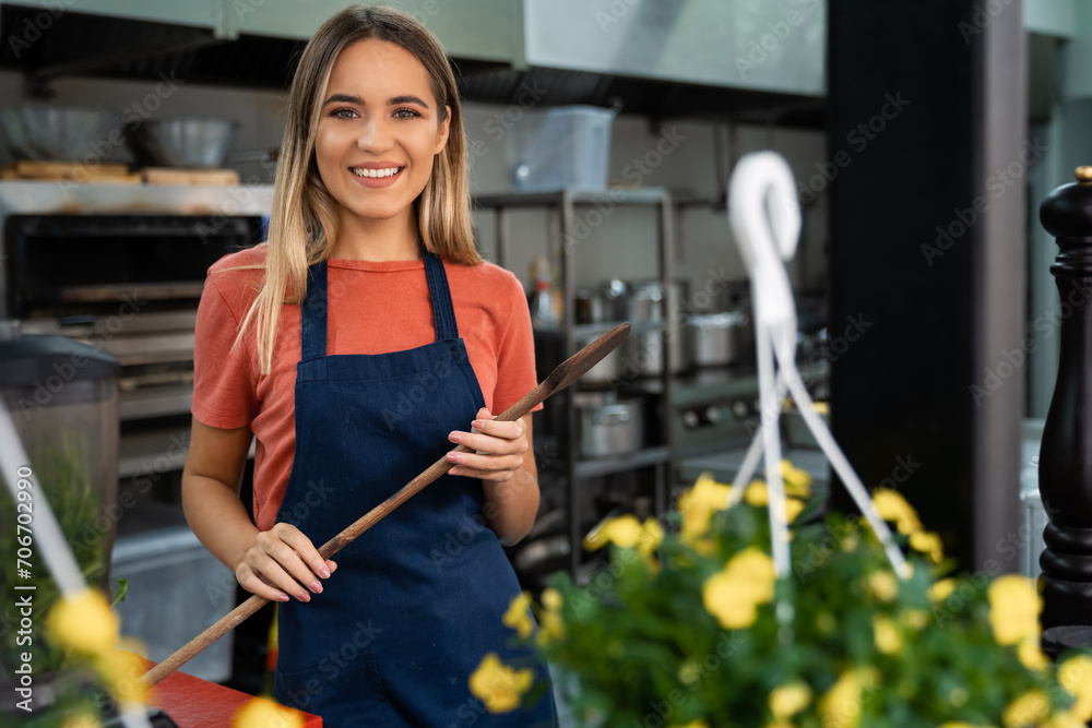Smiling confident young woman chef looking at camera holding large ...