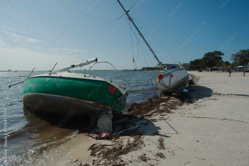 Two Damaged green and white Sailboat leaning to the right on the beach ...
