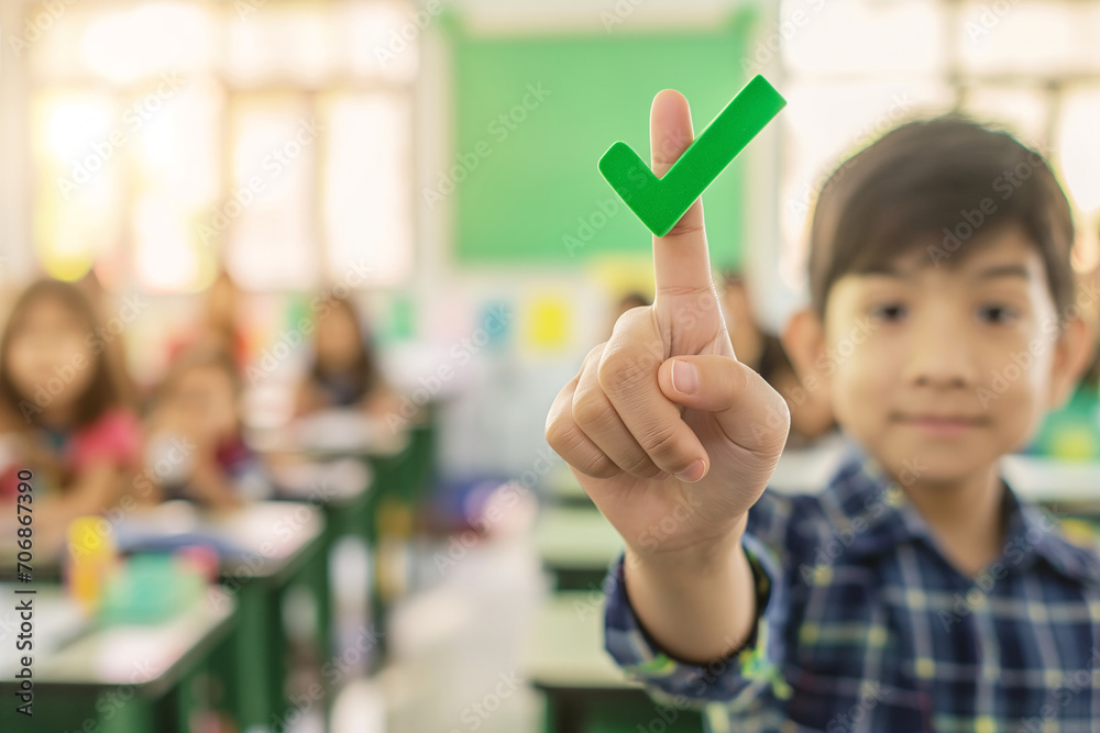 Schoolboy's hand and fingers pointing at a green 3D symbol or check ...