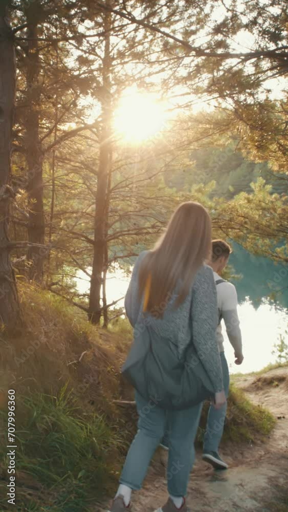 Vertical shot male female travelers walking hilly trail around lake ...