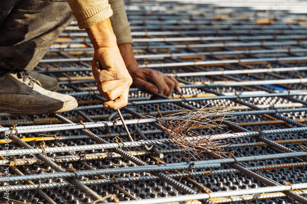 Ironworker securing steel rebar framing at construction site, worker ...