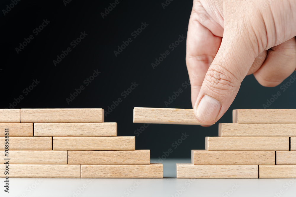 Hand put a piece of wood between the separated wall built with wooden ...