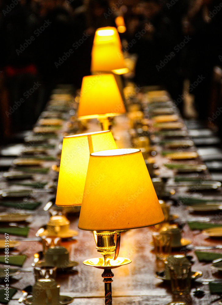 Classic lamps and cutlery in lines on the table in the dining hall of ...