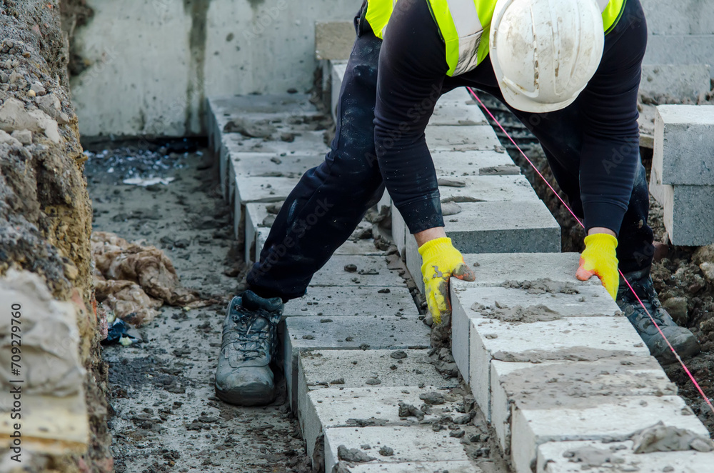 Hard working bricklayer laying concrete blocks on top of concrete ...
