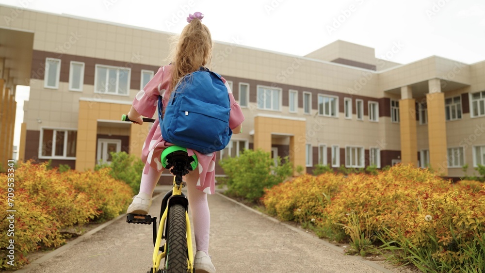 Little girl pupil with backpack riding on bike to elementary school ...