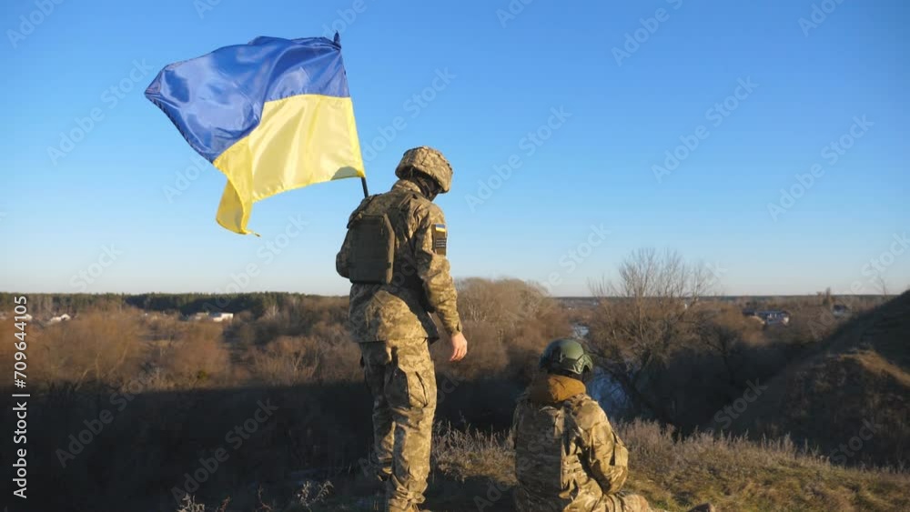 Military couple of ukrainian army sitting on lawn with Ukraine flag at ...
