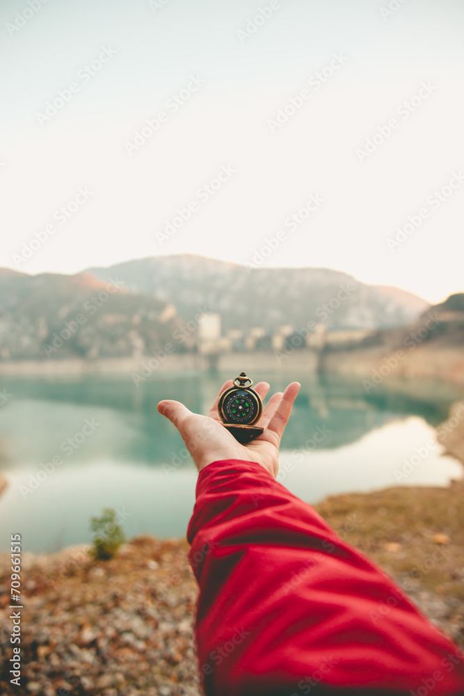 Anonymous hand holding a compass with a scenic lake and mountains in ...