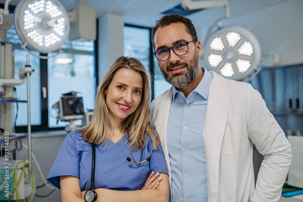 Portrait of confident doctor and nurse standing in examination room ...