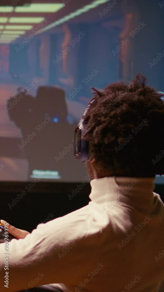 Vertical video African american man playing shooter videogame on ...