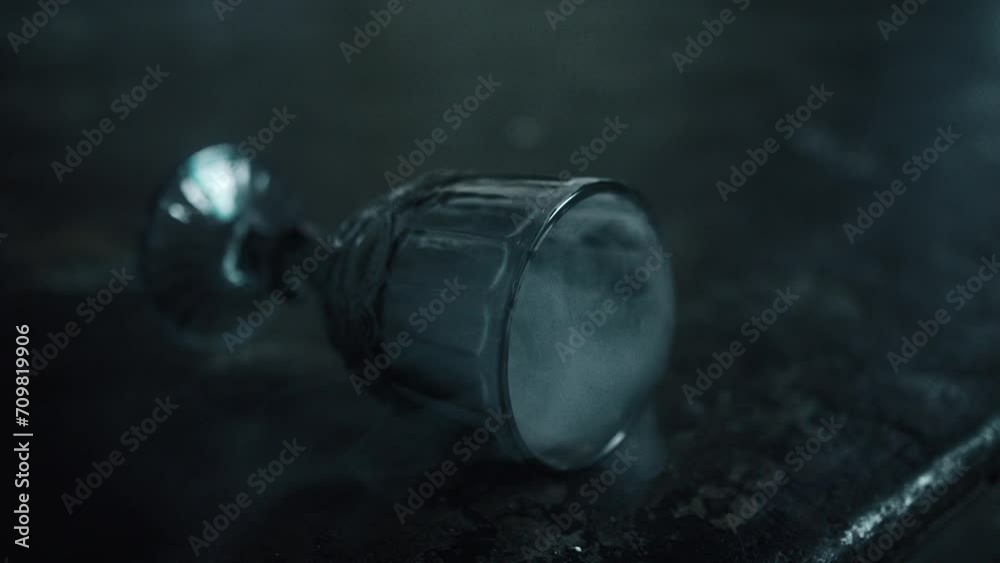 White smoke flies out of a glass goblet lying on the concrete floor ...