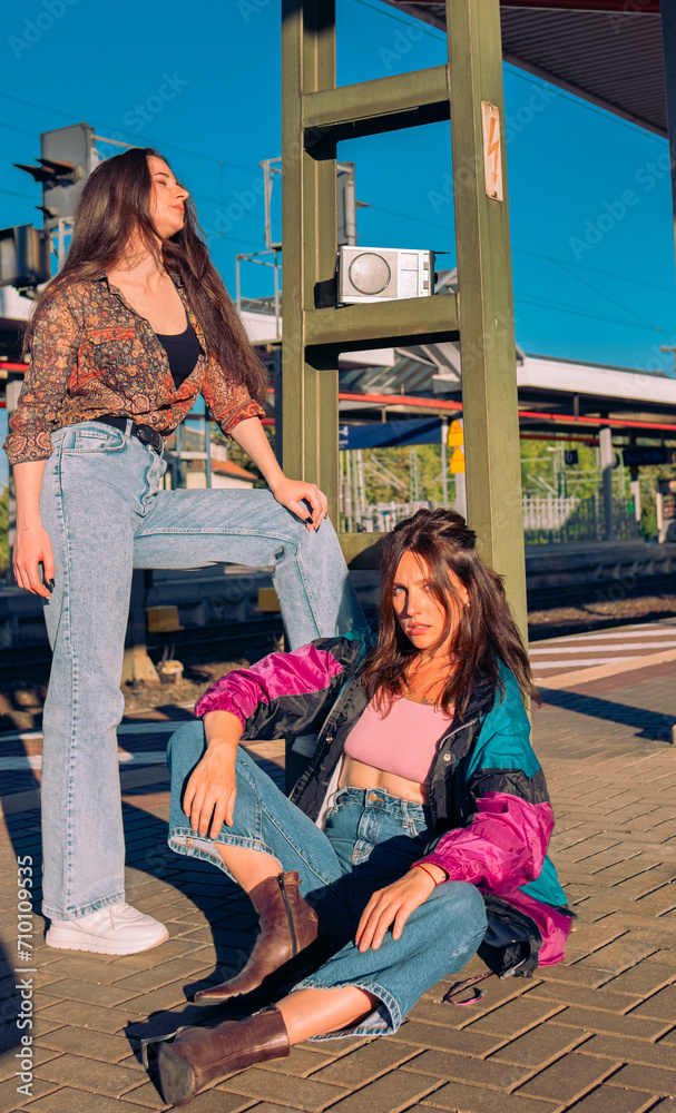 Two beautiful girls dressed in 90s style posing on the platform of the ...