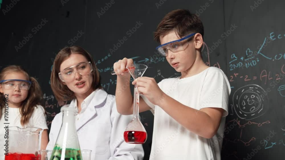 Vidéo Stock Smart boy pour chemical liquid in beaker while teacher ...