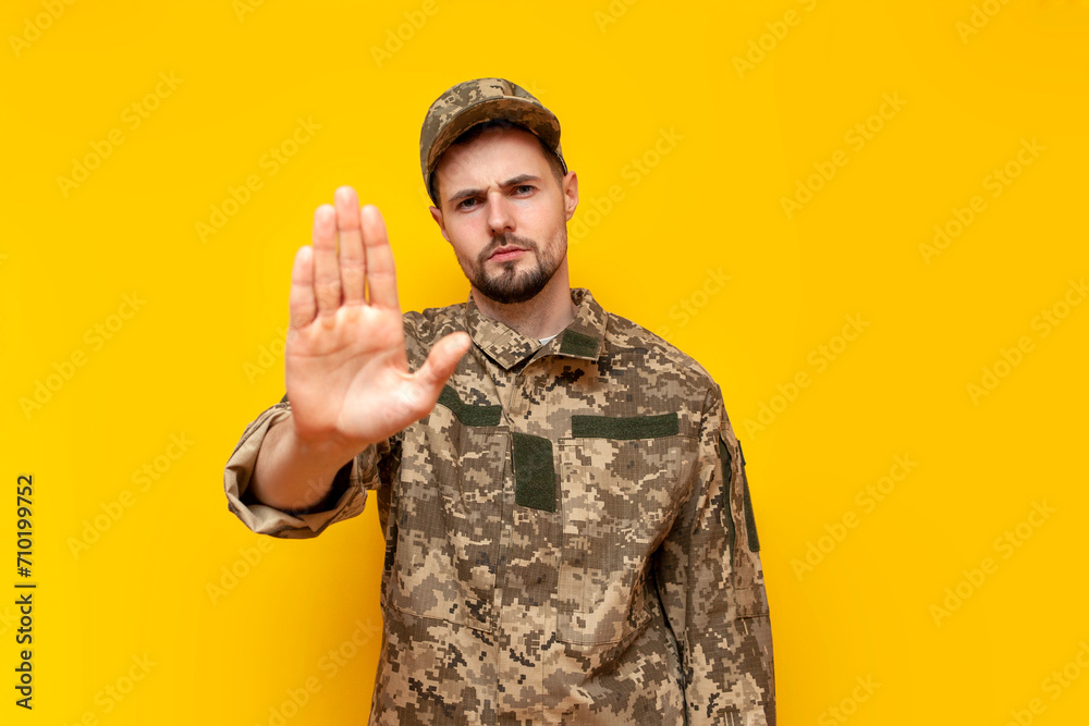 young Ukrainian male soldier in a camouflage pixel uniform shows a stop ...