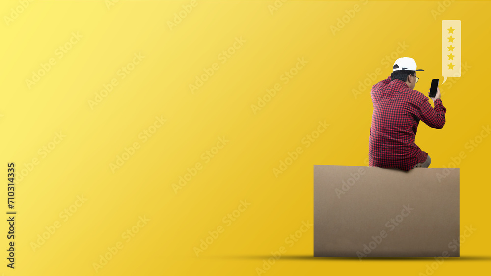 People in hat sit on the large packet for delivery while using mobile ...